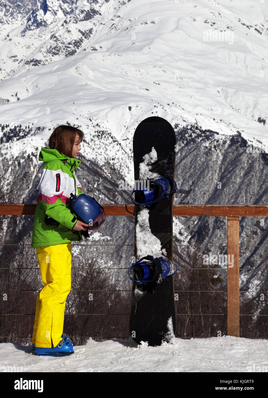Young snowboarder with helmet in hands and snowboard on viewpoint in ...