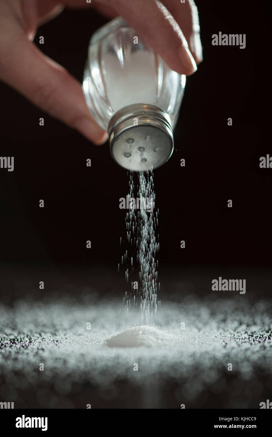 Adding salt. Backlight to salt from salt shaker. Close up Stock Photo ...
