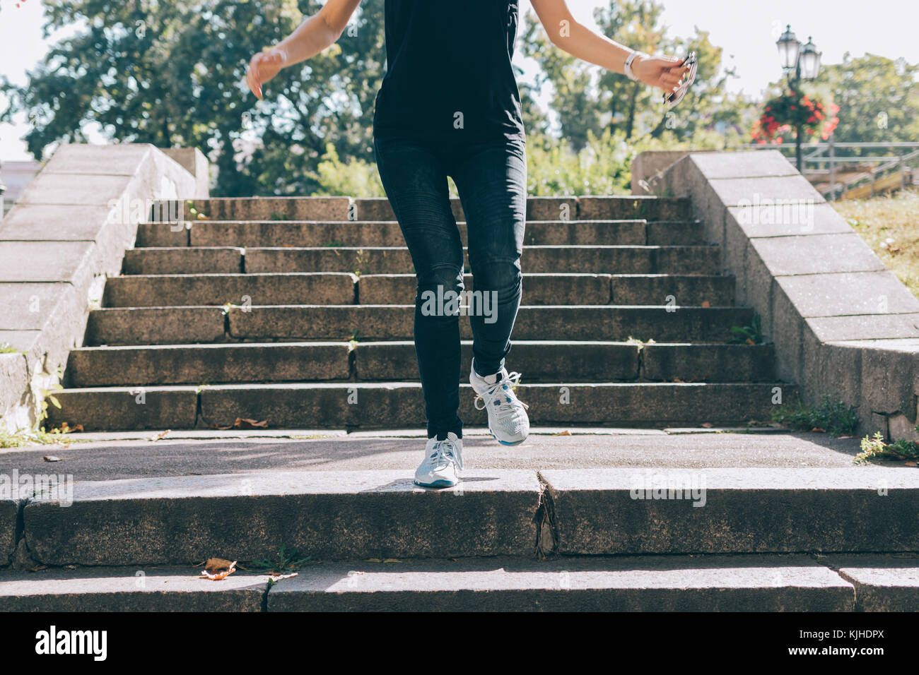 Young woman in jeans and sneakers, running down the stairs in the ...