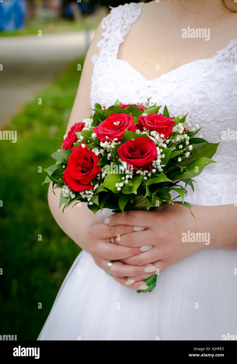 beautiful bride's red roses bouquet in hands of the bride Stock Photo ...