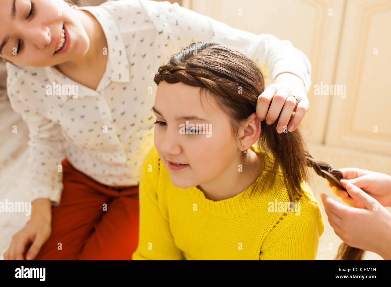 Three girls doing hair sitting on the floor in the room Stock Photo - Alamy