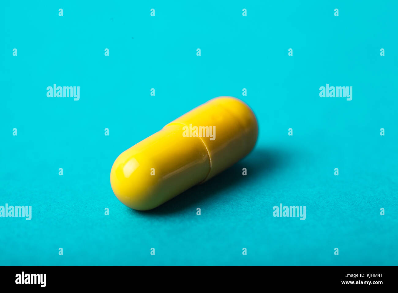 One yellow medicine pill closeup on bluebackground, medical concept ...