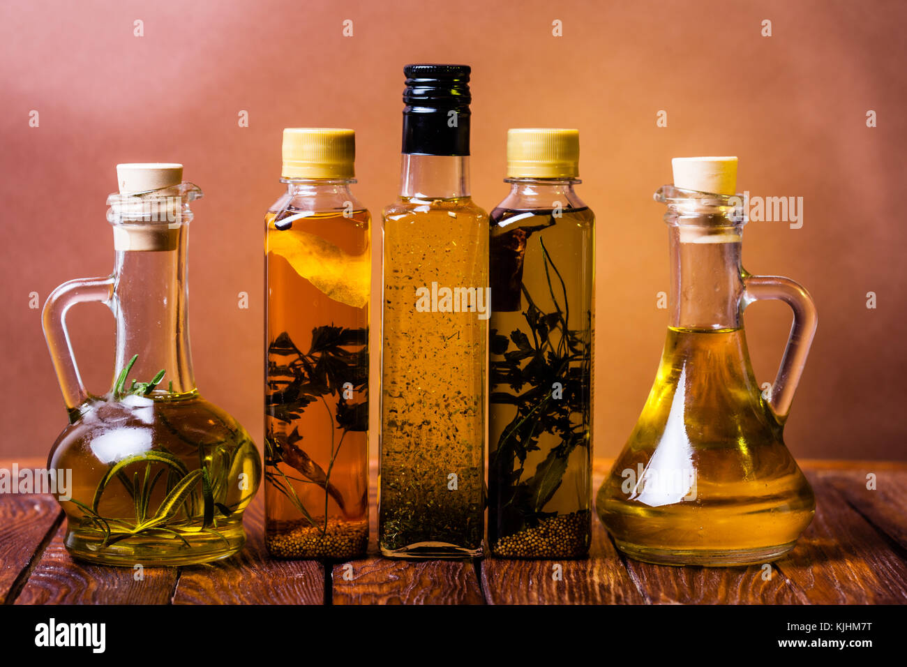 Assortment of spicy oils with herbs and spices in different bottles ...