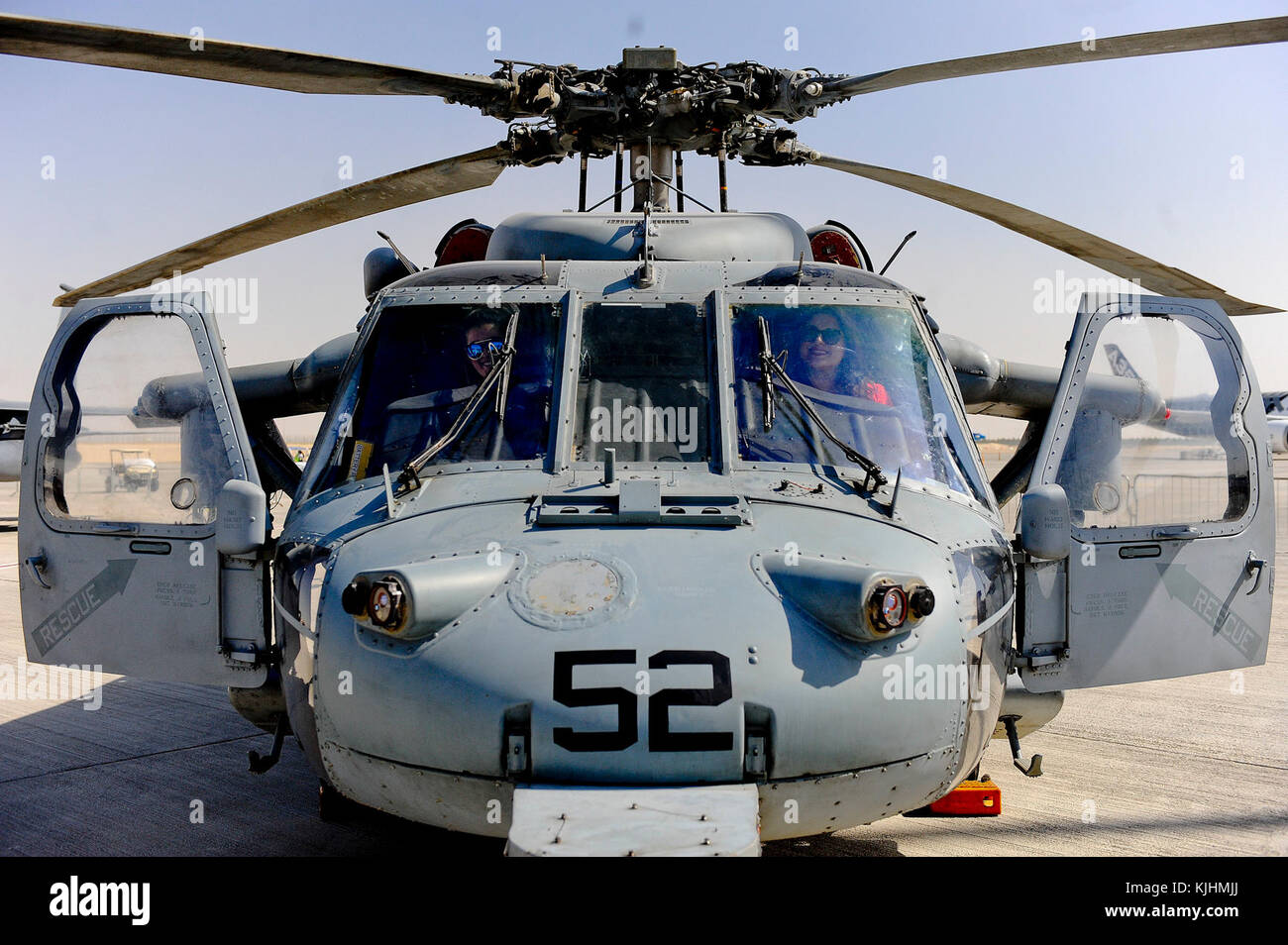 Spectators sit in the cockpit of a U.S. Navy MH-60S Seahawk static ...