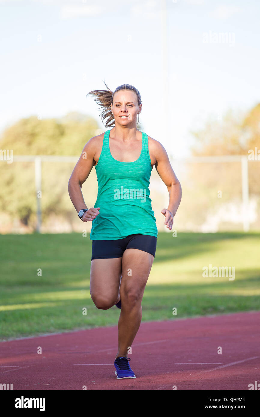 Close up wide angle view of a female sprinter athlete getting ready to ...