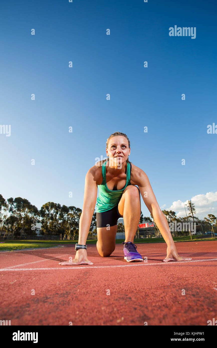 Close up wide angle view of a female sprinter athlete getting ready to ...