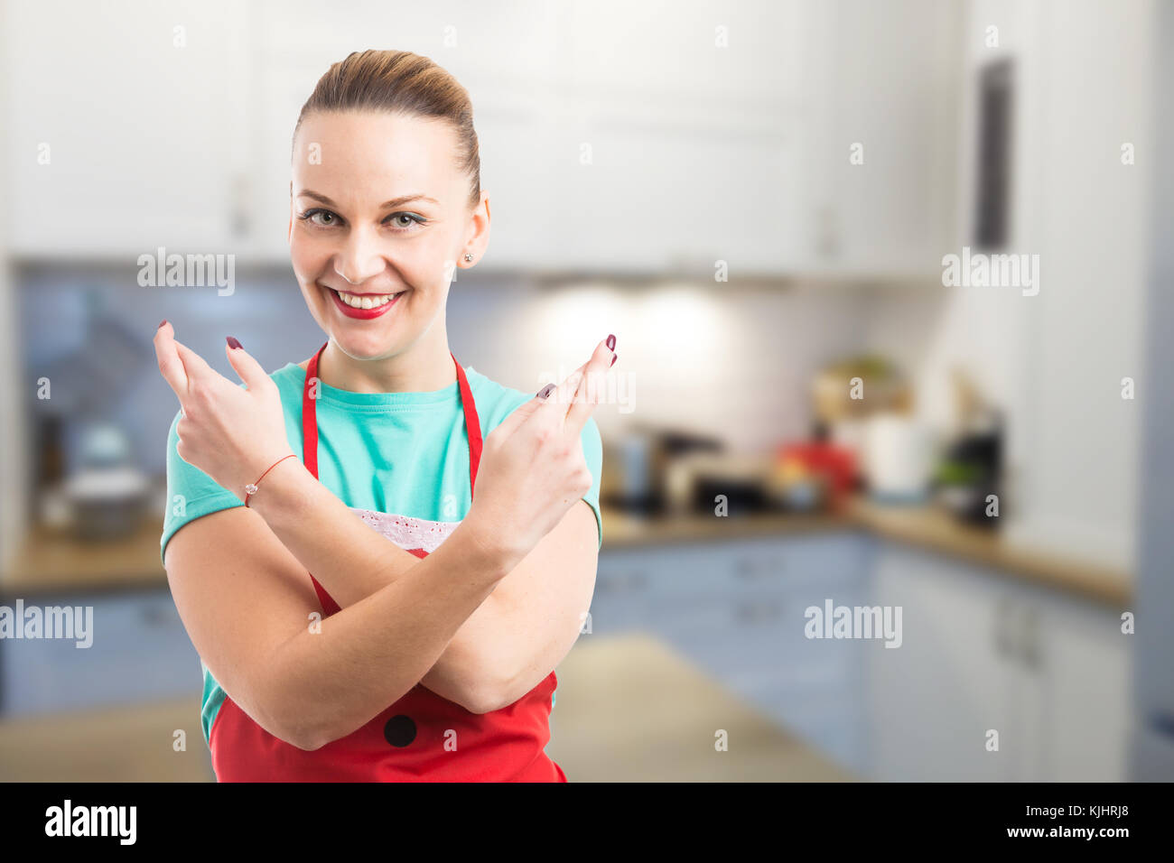 Happy housewife making good luck gesture with fingers crossed on both ...