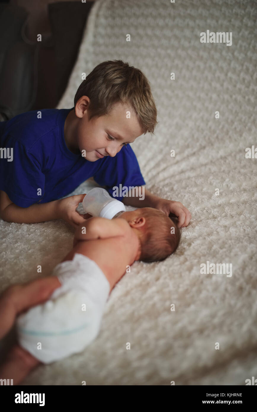 boy feeding newborn baby with bottle of milk Stock Photo - Alamy