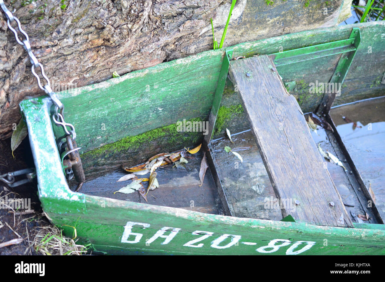 The old boat is tied to a tree trunk by a chain Stock Photo - Alamy