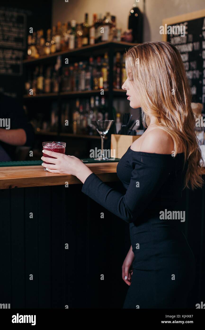 Woman standing at the bar with a cocktail Stock Photo - Alamy