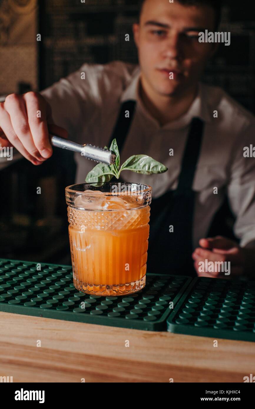 Barman decorating cocktail with basil Stock Photo - Alamy