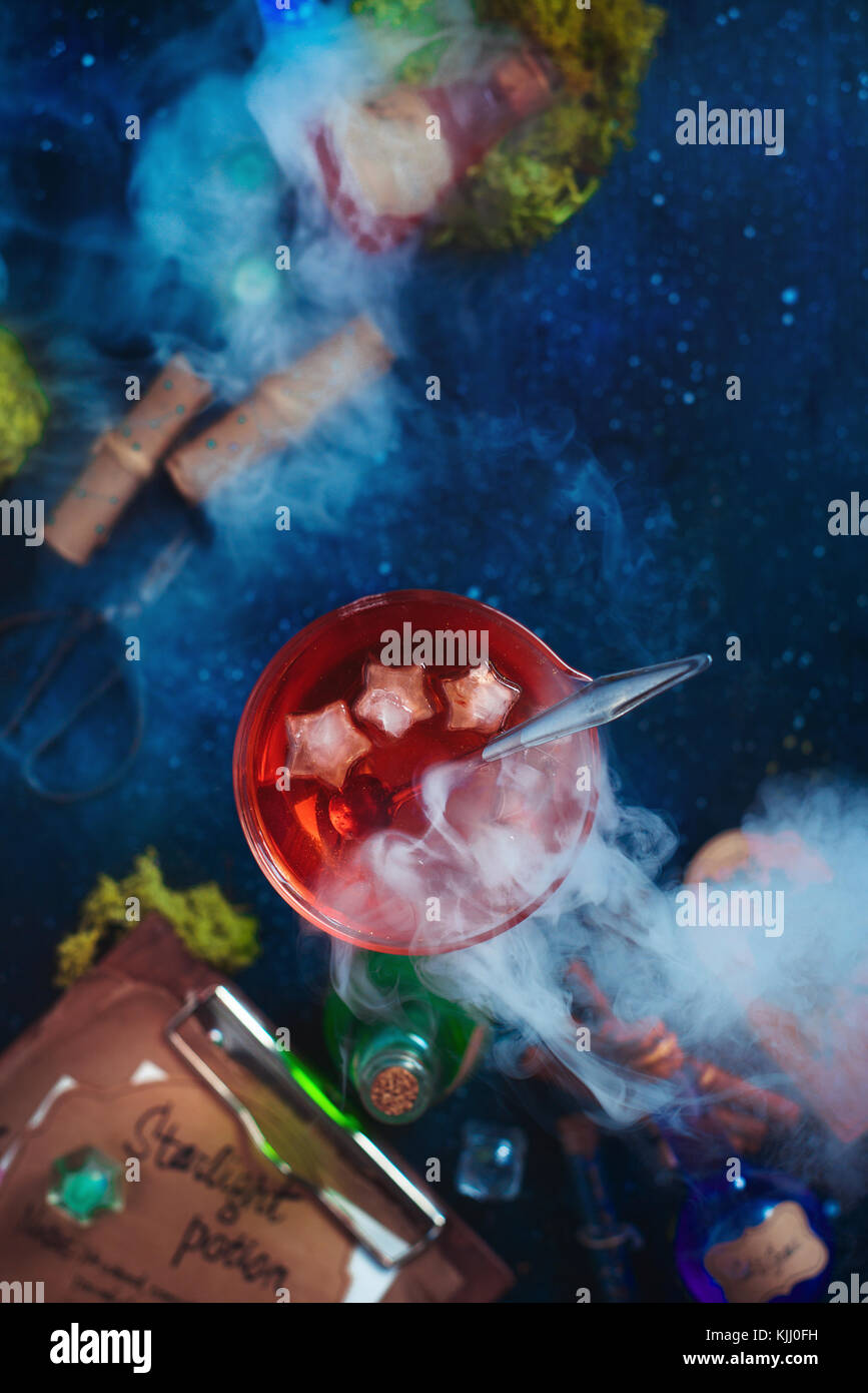 Boiling bowl with red steaming potion and star ice cubes.Magical still ...