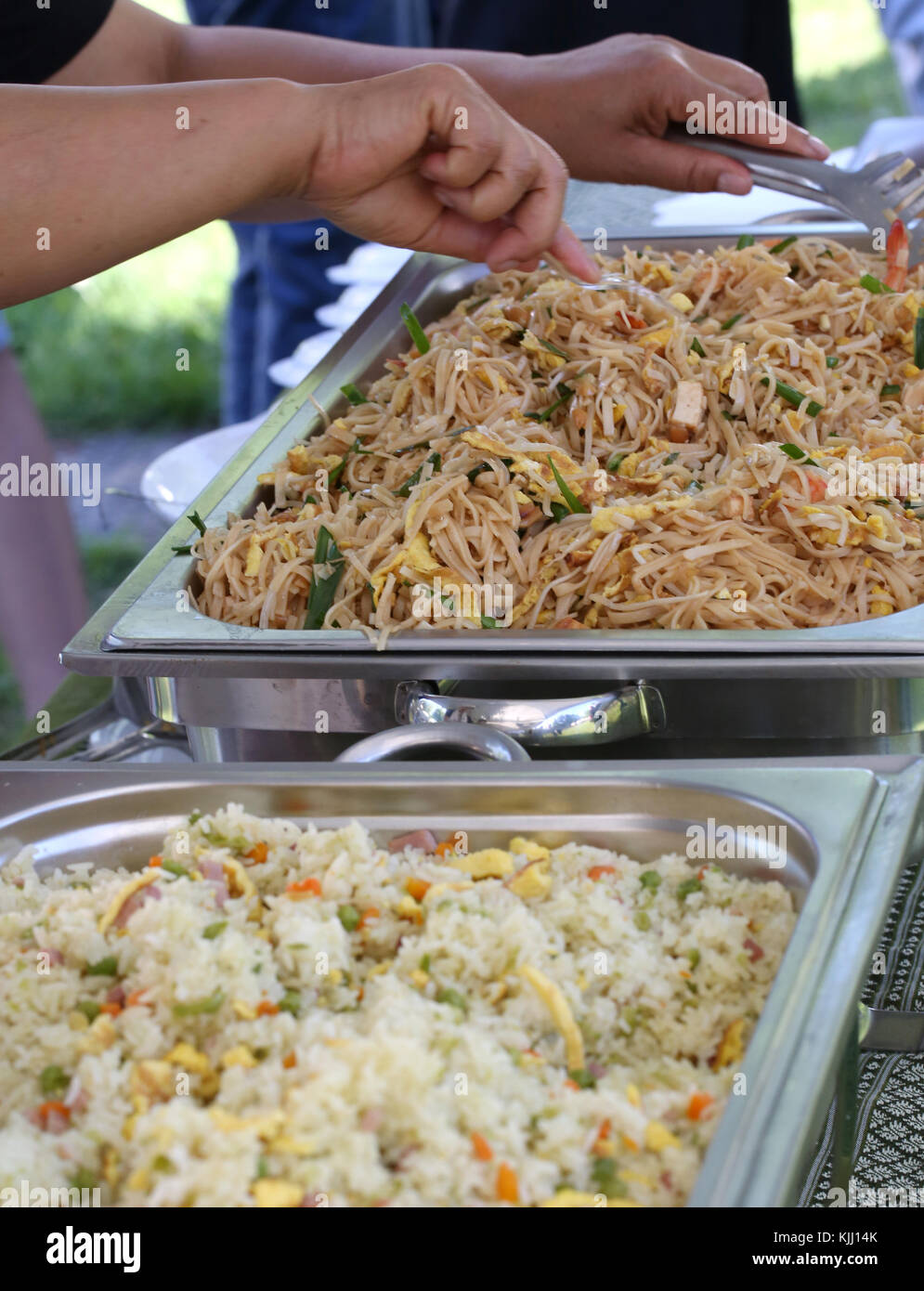 cook prepares noodles trays with vegetable and egg and shrimp typical ...