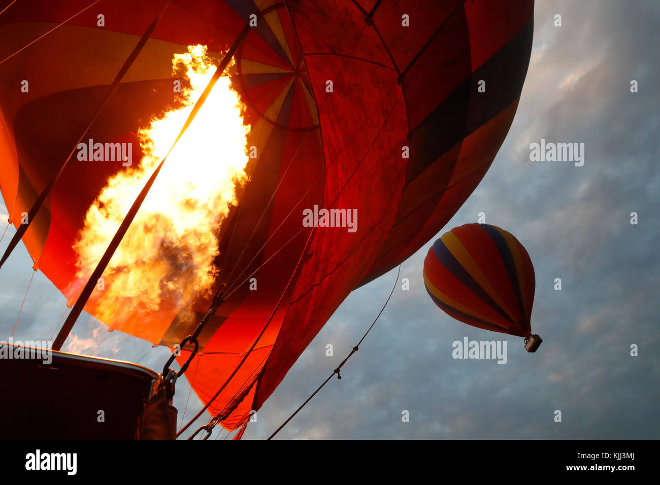 A gas jet flame fills a hot air balloon at dawn for a tourist flight ...