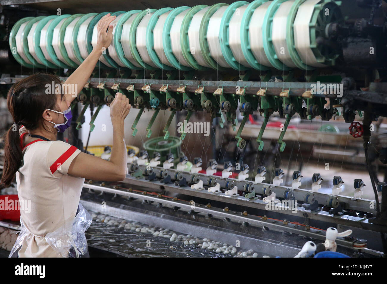 Traditional silk factory. Woman working on silk spinning machine. Dalat ...