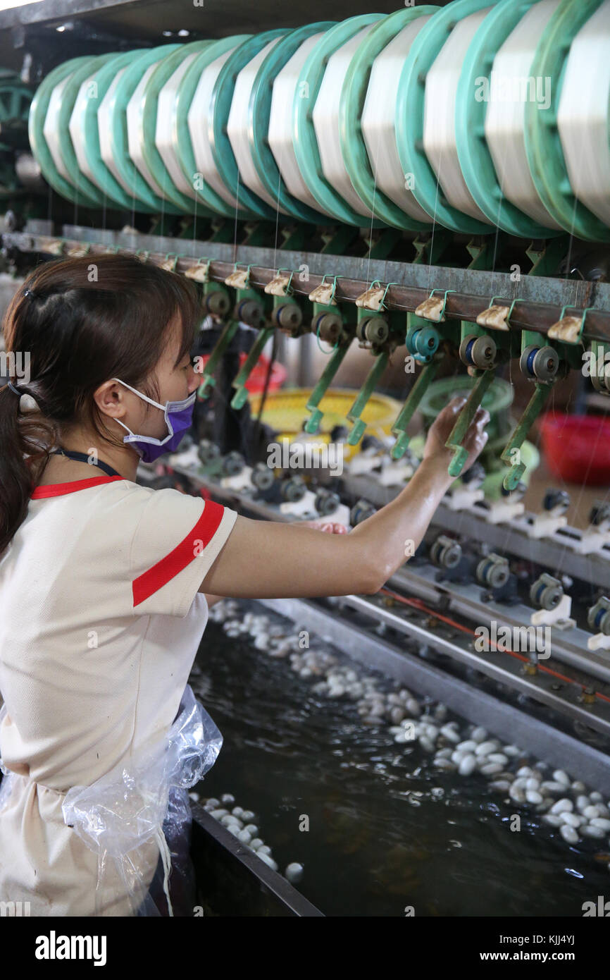 Traditional silk factory. Woman working on silk spinning machine. Dalat ...