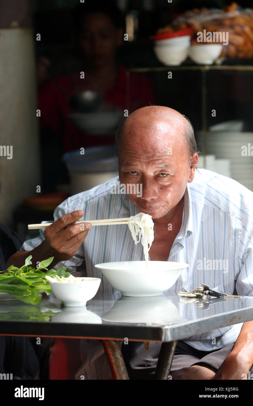 Man eating vietnamese soup( pho ) in a street restaurant. Ho Chi Minh ...