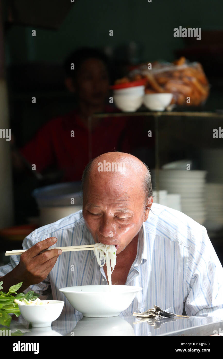 Man eating vietnamese soup ( pho ) in a street restaurant. Ho Chi Minh ...