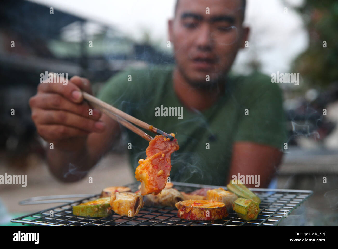 Man eating vegetables. Barbecue. Thay Ninh. Vietnam Stock Photo - Alamy
