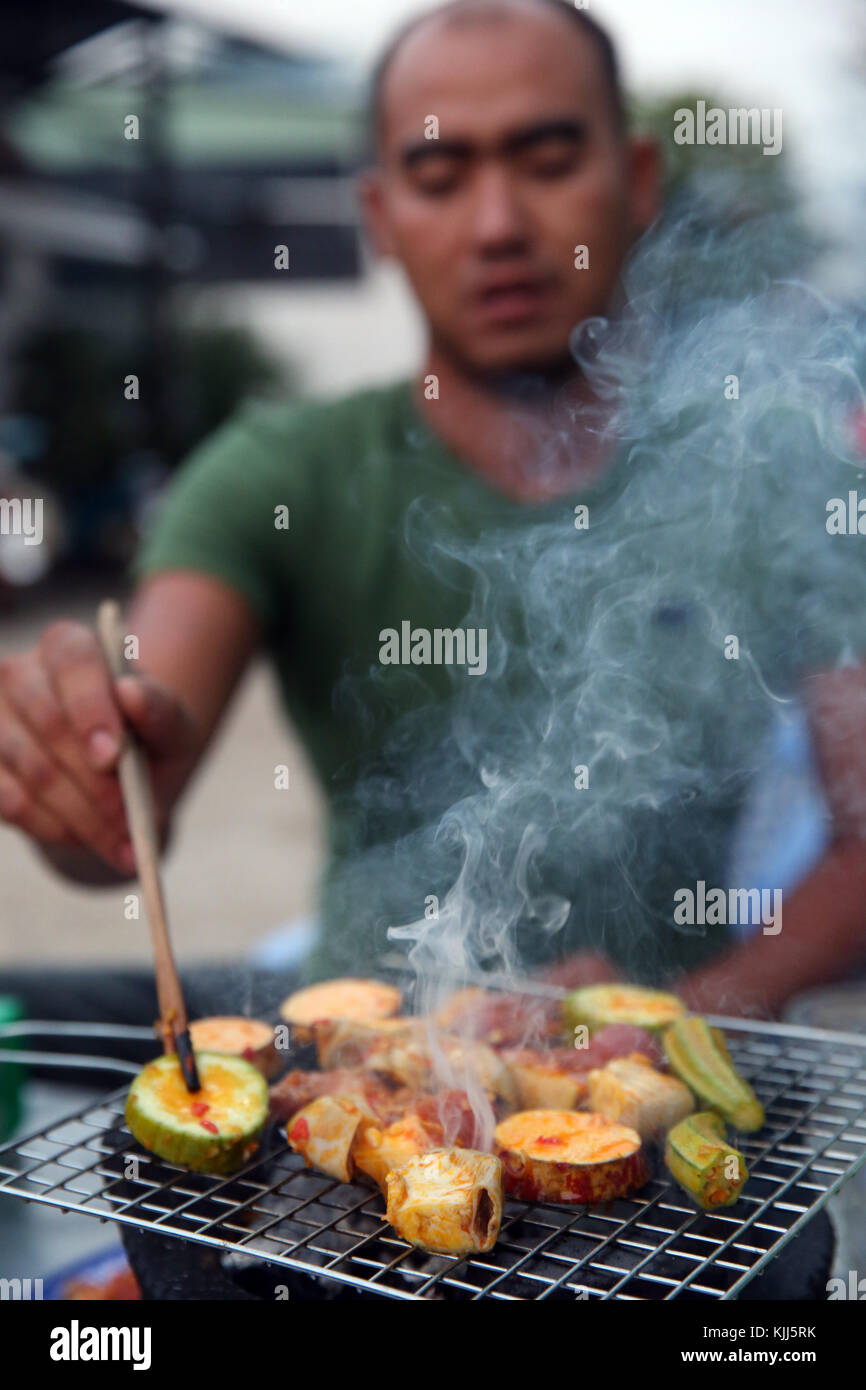 Man eating vegetables. Barbecue. Thay Ninh. Vietnam Stock Photo - Alamy