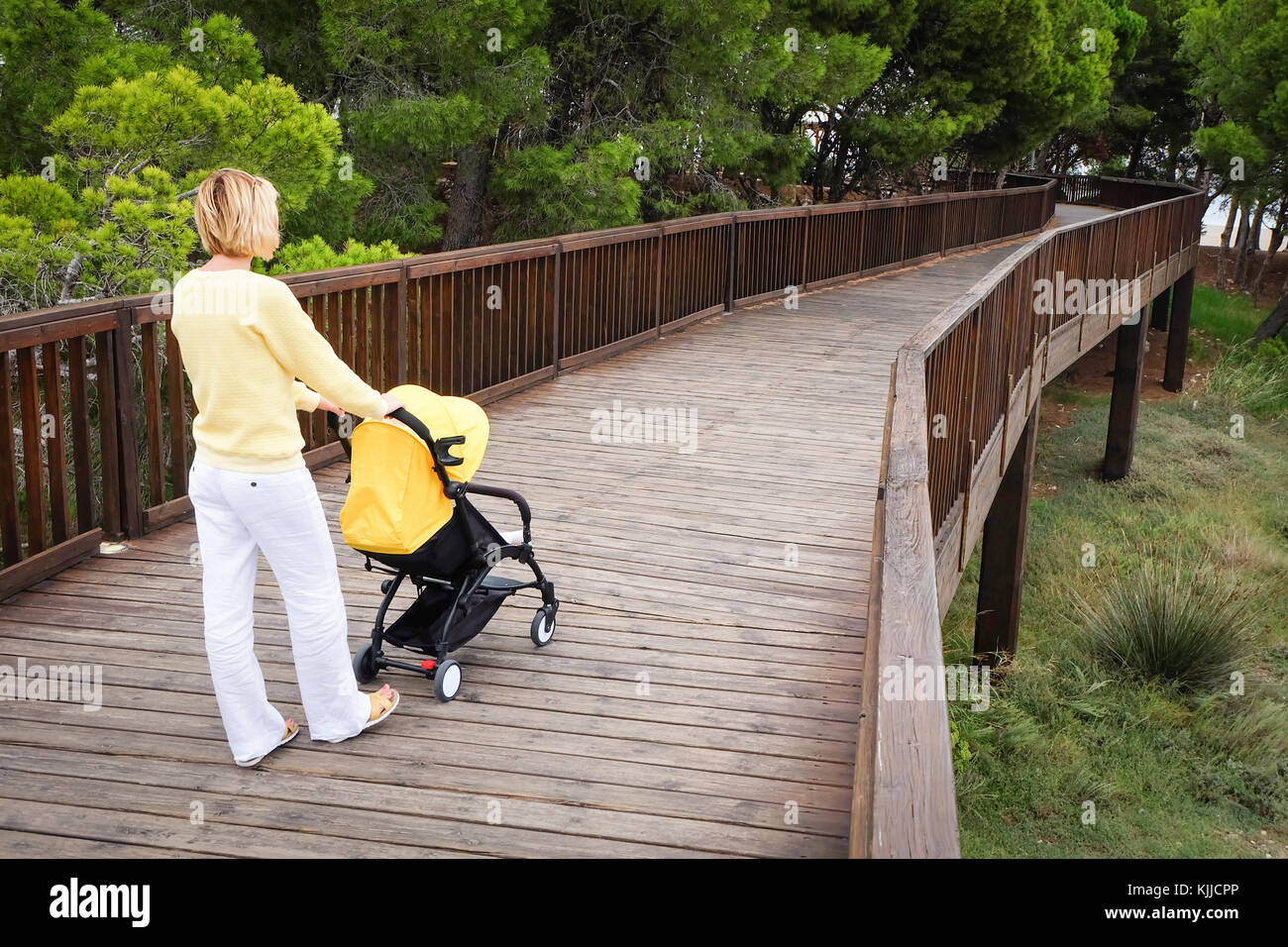 Young woman strolling a baby carriage on wooden bridge Stock Photo - Alamy
