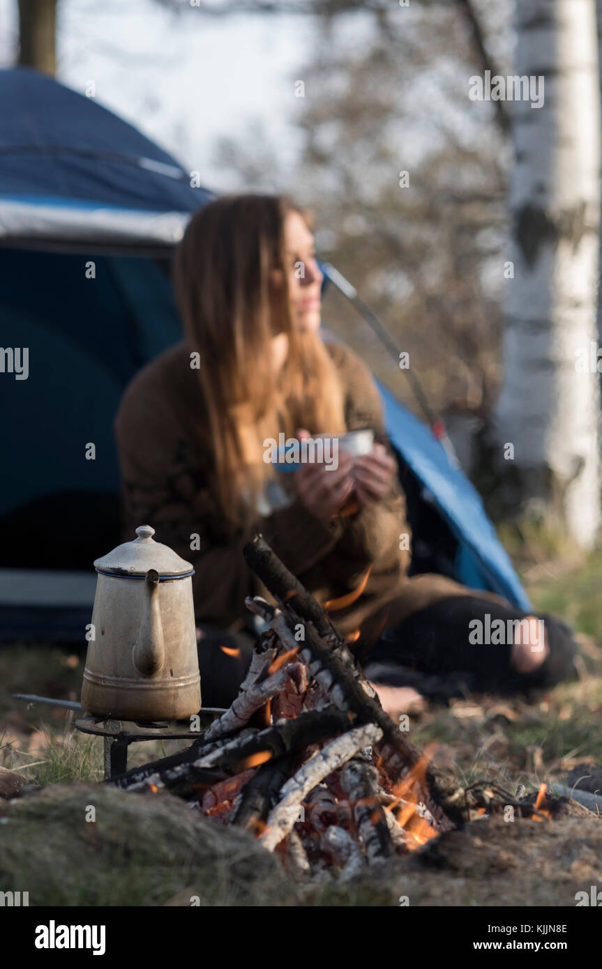 Woman camping at campfire in forest Stock Photo - Alamy
