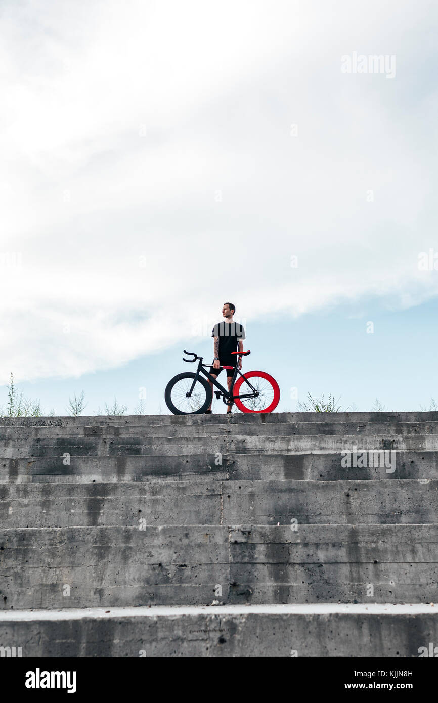 Young man standing with fixie bike on concrete steps Stock Photo - Alamy