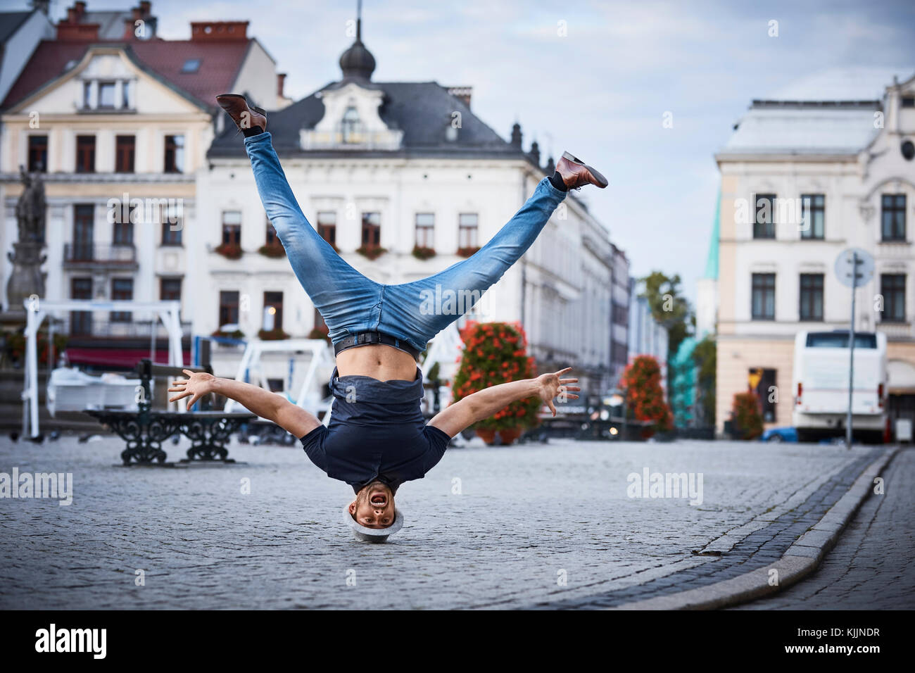 Man having fun doing headstand on square in the city Stock Photo - Alamy