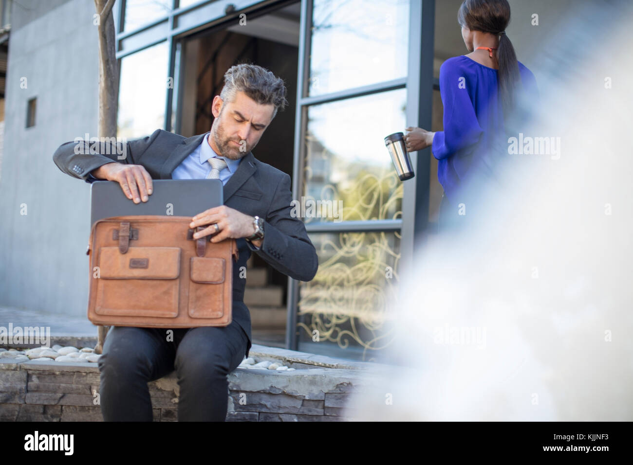 Businessman putting his laptop into his bag Stock Photo - Alamy