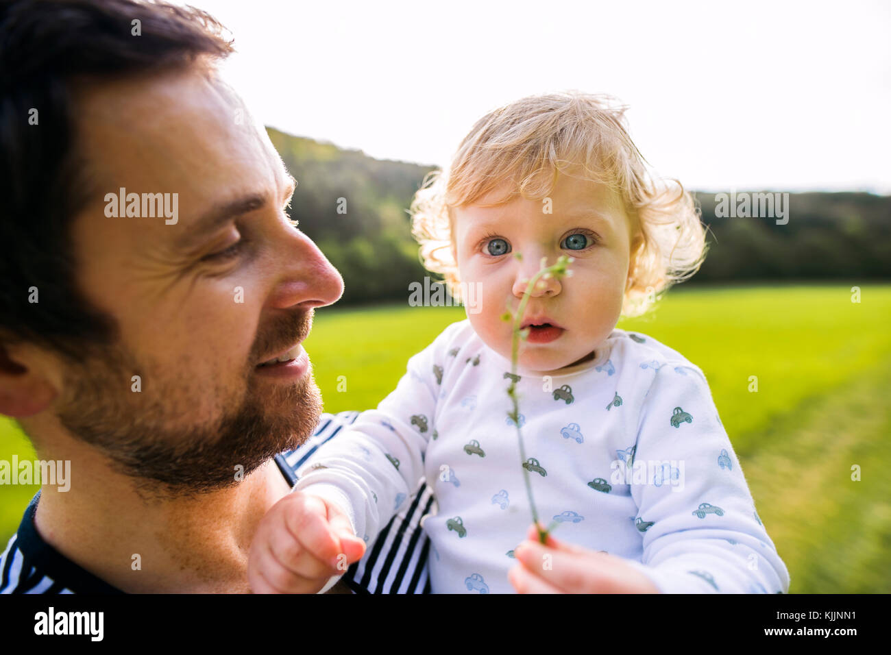 Father holding cute little boy on meadow with plant Stock Photo - Alamy