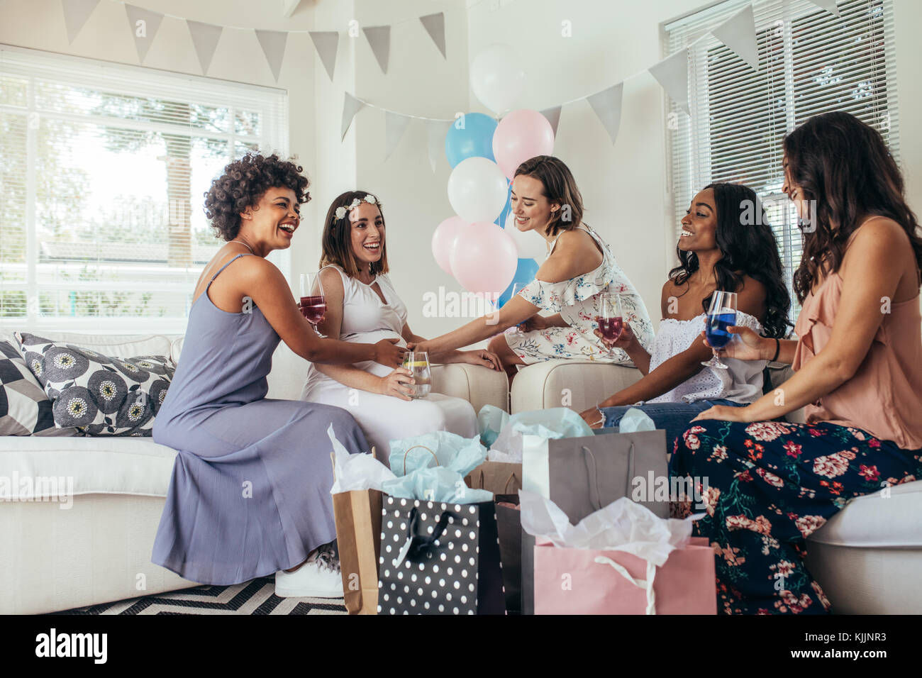 Group of multiethnic female friends attending baby shower at home ...