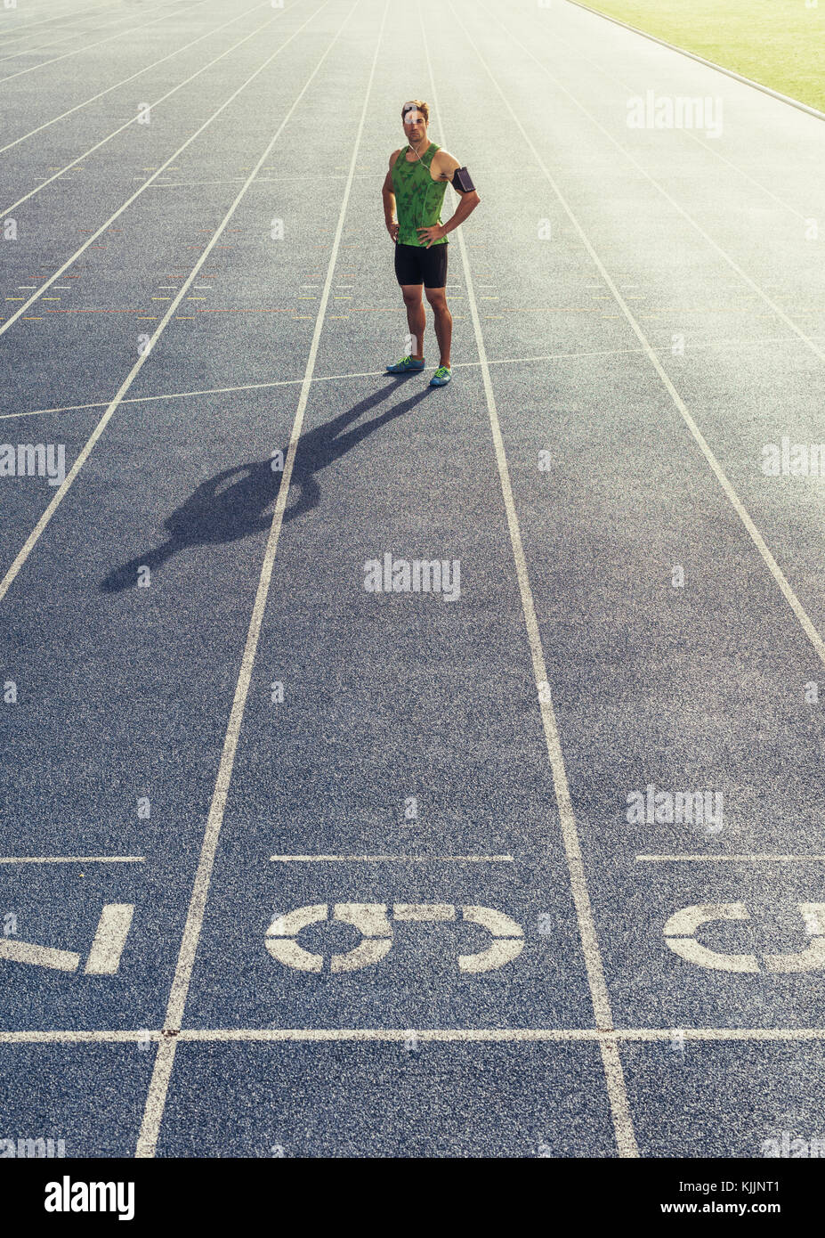 Runner standing on running track with hands folded. Athlete wearing ...