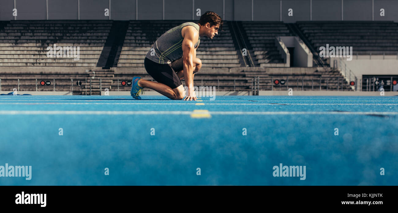 Side view of an athlete on his marks to start off the run. Runner ...