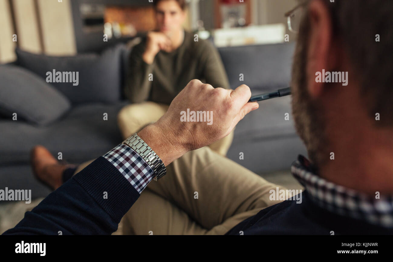Hands of psychologist holding a pen and listening to man during therapy ...