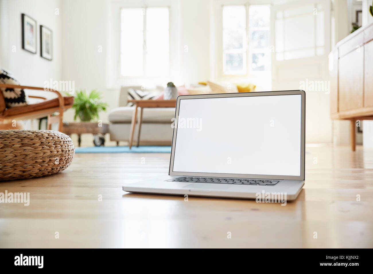 Laptop standing on wooden floor in a bright modern living room of an ...