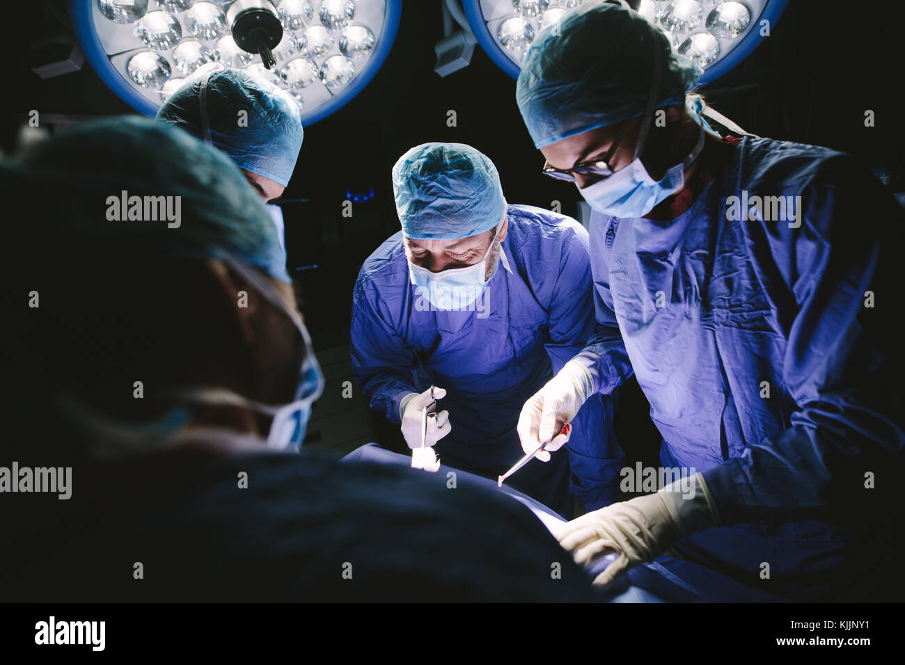 Team of professional surgeons performing surgery in operation room ...