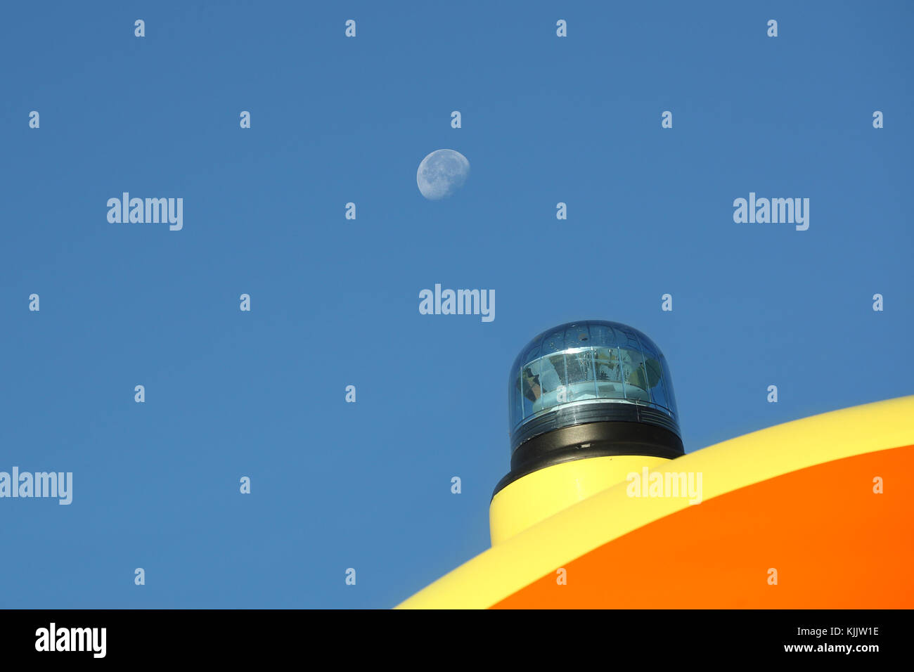 Detail of roof and blue emergency light against a blue sky with moon ...
