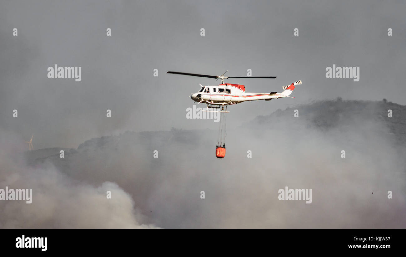 Fire helicopter with water tank against smoke Stock Photo - Alamy