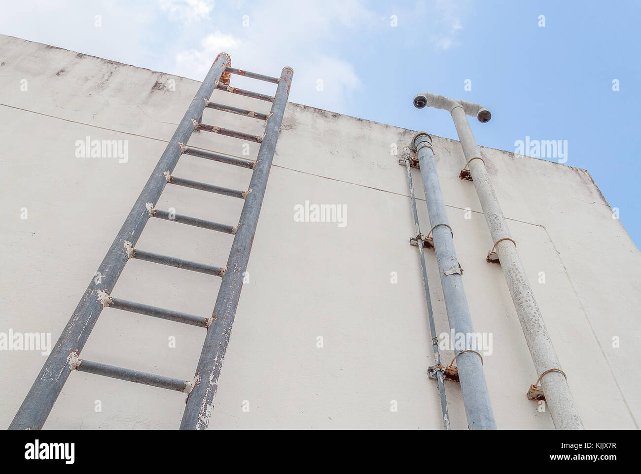 Old vertical industrial metal rusted ladder. Staircase to blue sky with ...