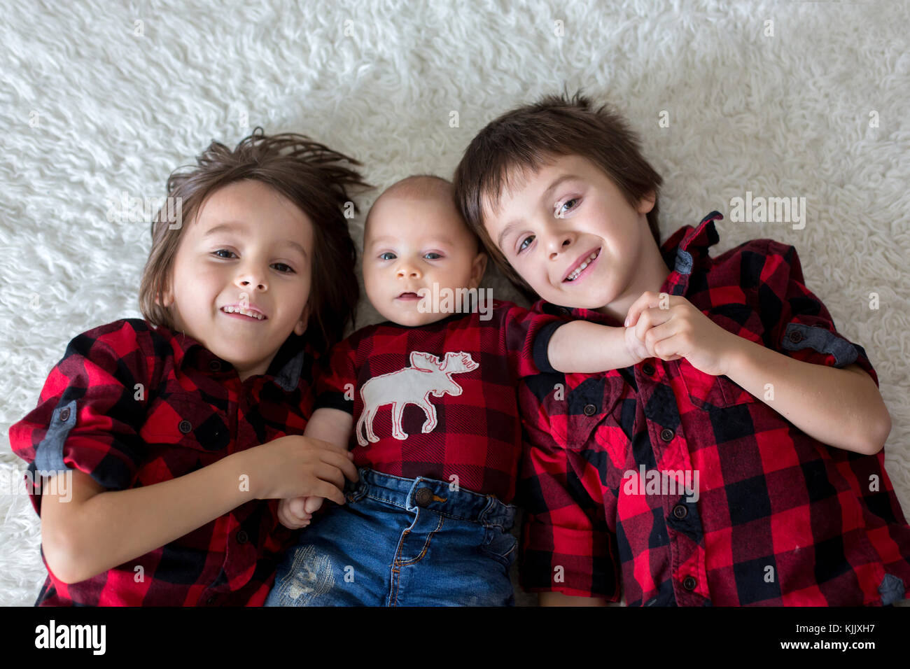 Portrait of three happy children, boy brothers, lying on the floor on ...