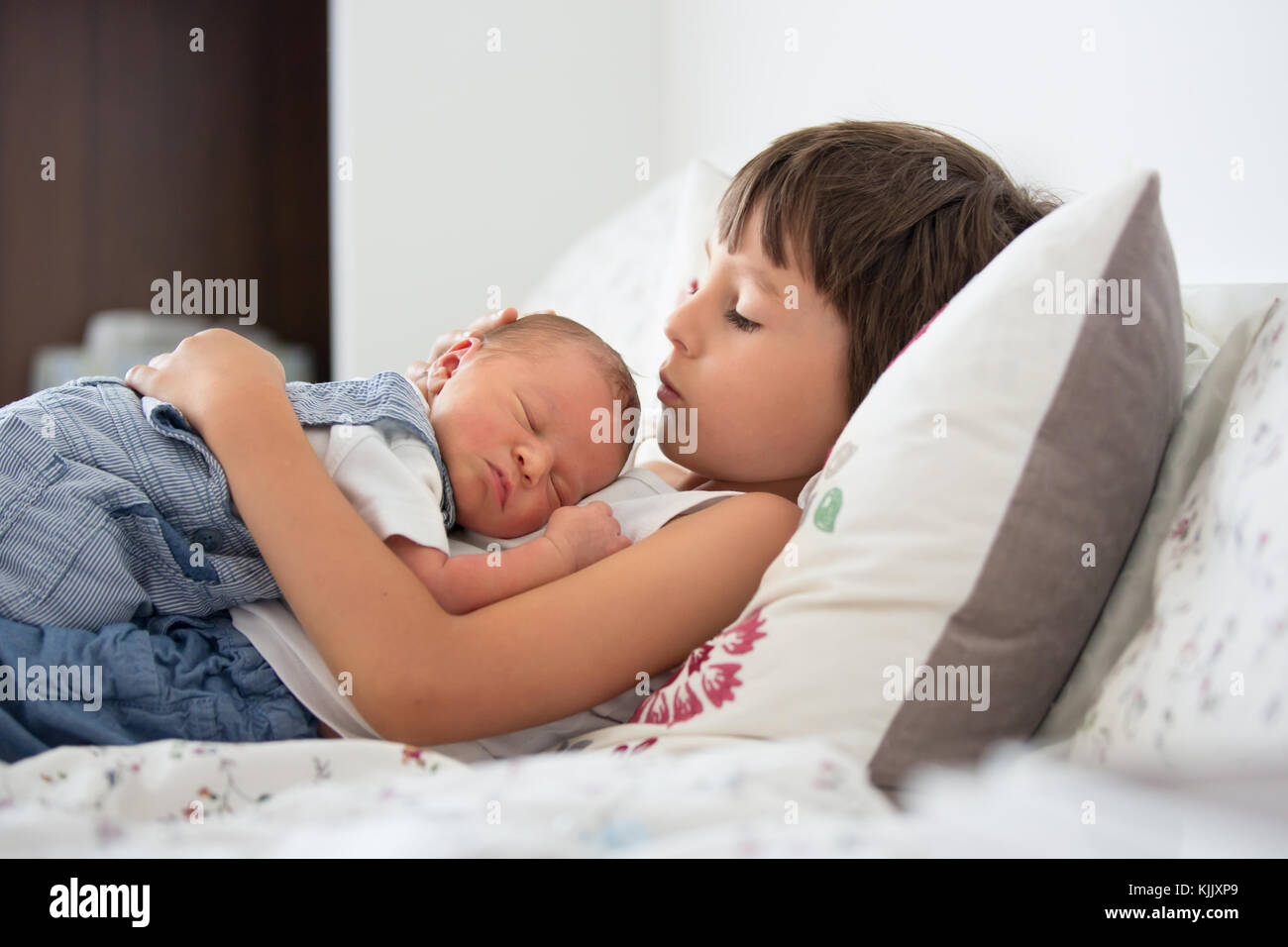 Beautiful boy, hugging with tenderness and care his newborn baby ...