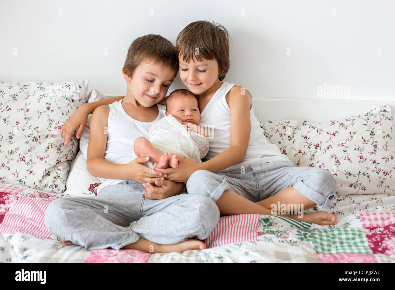 Two children, toddler and his big brother, hugging and kissing their ...