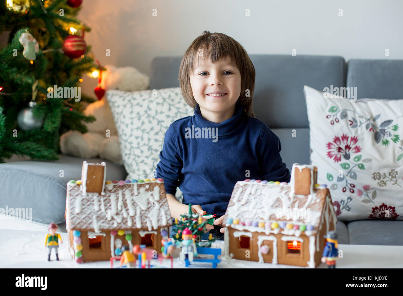 Cute child, boy, playing with gingerbread houses and little toys at ...
