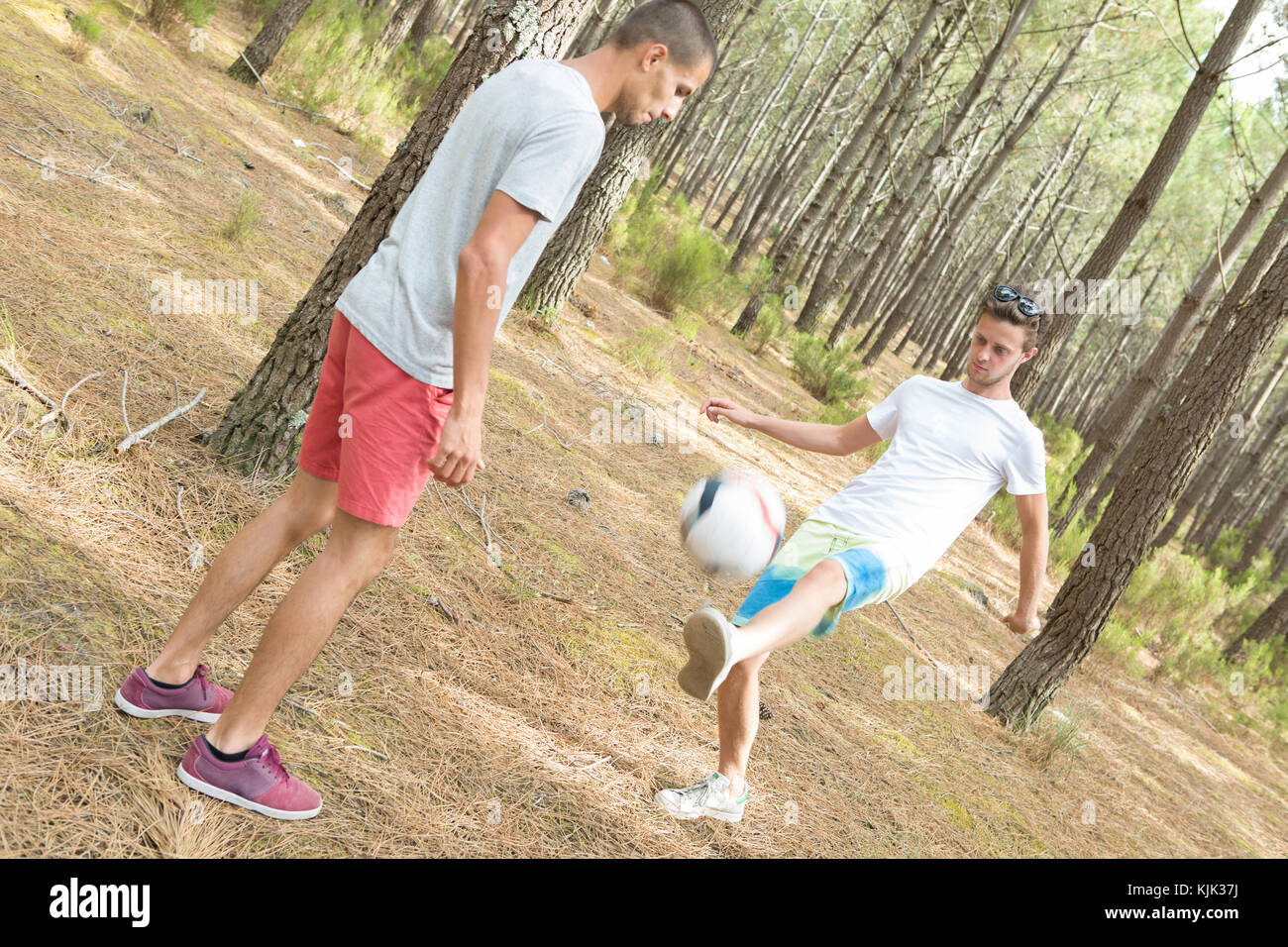 Young men playing football in forest Stock Photo - Alamy