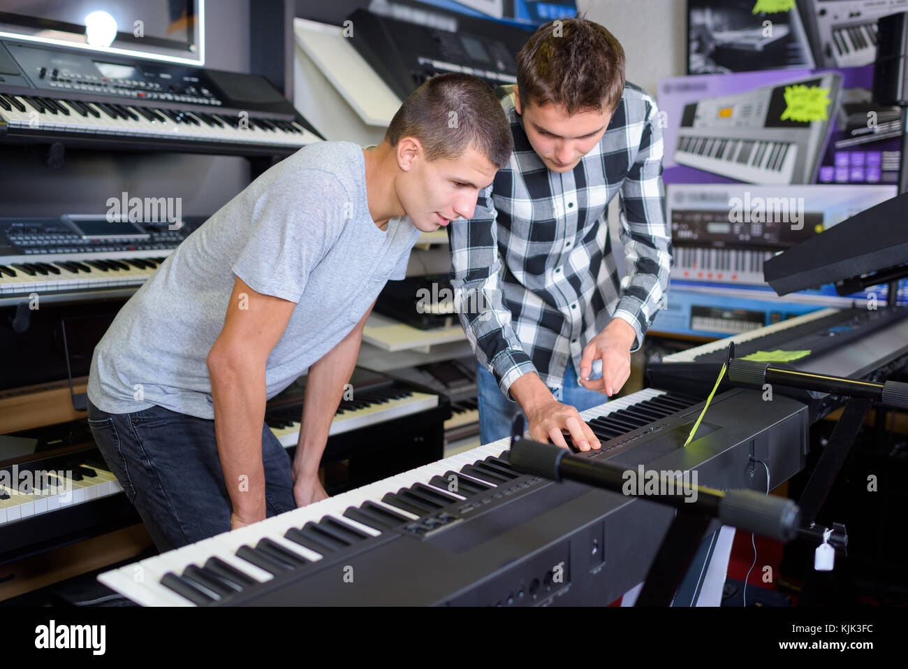 Young men looking at keyboards in musical shop Stock Photo - Alamy