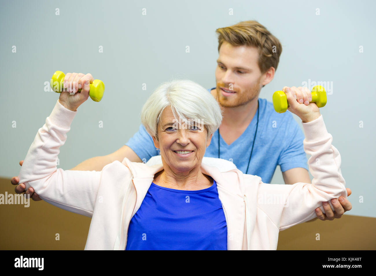 senior woman lifting dumbbells in fitness with a trainer Stock Photo ...