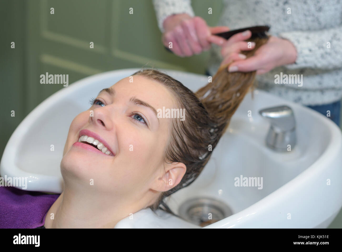 Hairdresser combing wet hair over sink Stock Photo - Alamy