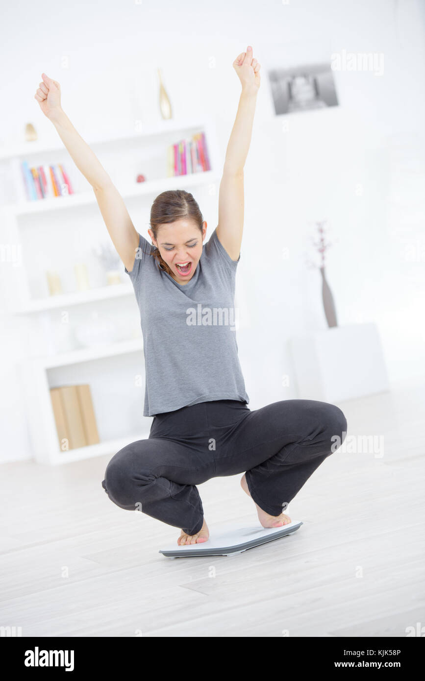 Jubilant lady on bathroom scales Stock Photo - Alamy
