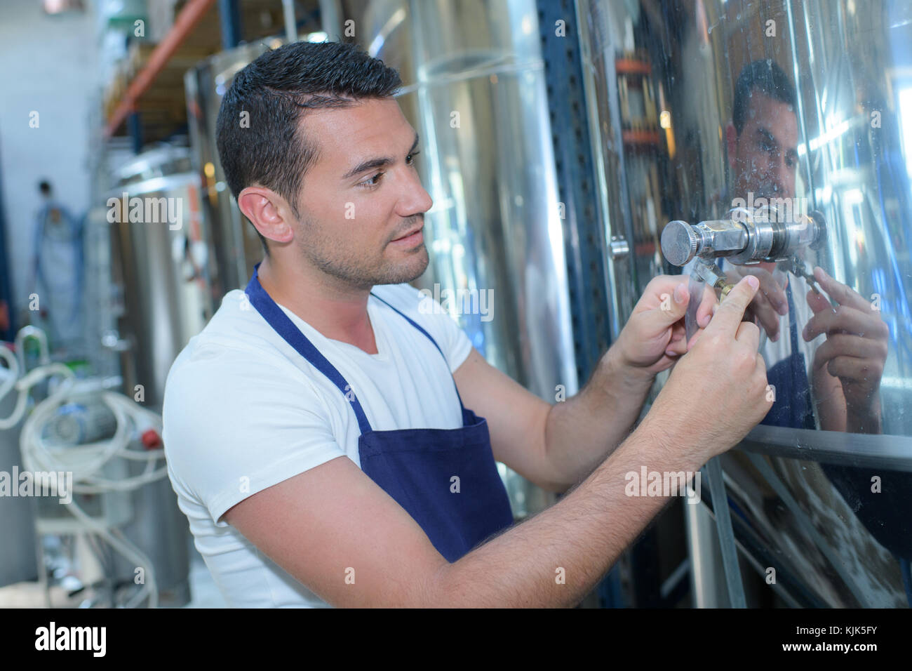 manufacturer filling beer into glass from storage tank at brewery Stock ...