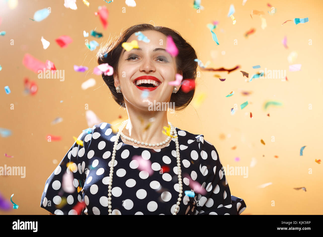 Happy girl on yellow background, colorful confetti slowly scatter and ...